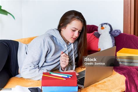 노트북과 교과서를 사용하여 집에서 공부하는 침대에 누워 예쁜 십대 학생 소녀 온라인 원격 교육 개념입니다 가정 생활에 대한 스톡 사진 및 기타 이미지 Istock
