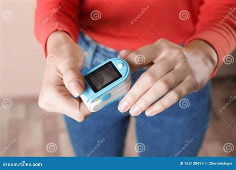 Young Woman Checking Pulse With Digital Medical Device Indoors Stock