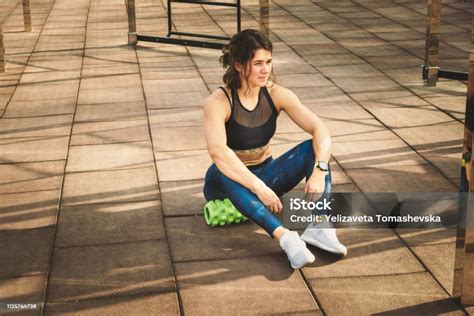 테마 스포츠와 재활 스포츠 의학입니다 아름 다운 강한 슬림 백인 여자 선수 앉아 다음 거품 롤러 녹색 필드 거리 운동 통증 제거 스트레칭 하 고 근육을 마사지 가냘픈에 대한