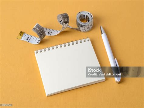 노란색 텍스처 배경에 센티미터 와 인치 측정 테이프의 복사 공간 흰색 펜및 롤종이 메모장을 엽니 다 건강한 식습관 다이어트 체중