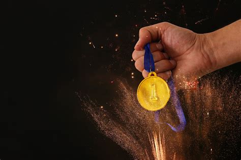 남자 손 검은 배경과 불꽃놀이 오버레이 대 한 골드 메달을 들고 수상 및 승리 개념입니다 Championship에 대한 스톡