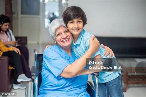 Smiling Indian Senior Woman Granny Sit In Wheelchair Hug Her Grandson