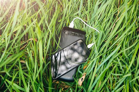 스마트 폰과 블랙 파워 뱅크는 녹색 잔디에 Usb로 누워 있다 현대 정보 기술 사진 배터리 충전기 여름 자연에서 휴대 전화와 함께 여행 Usb 케이블에 대한 스톡 사진 및