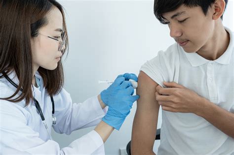 의사가 주사기를 들고 바이러스의 확산을 방지하기 위해 클리닉에서 환자를 예방 접종하려고했습니다 14 15 살에 대한 스톡 사진