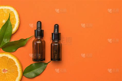 鲜橙片，树叶和药瓶在橙色的背景上。