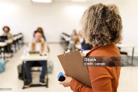 교수가 클립보드와 화이트보드 지우개를 들고 강의하는 동안 교실에 대한 스톡 사진 및 기타 이미지 교실 노트북 단체