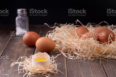 건초의 둥지배경에 건초에 흰색과 노른자와 오픈 계란은 완전히 신선한 계란 소금입니다 나무 배경입니다 공간을 복사합니다 텍스트를