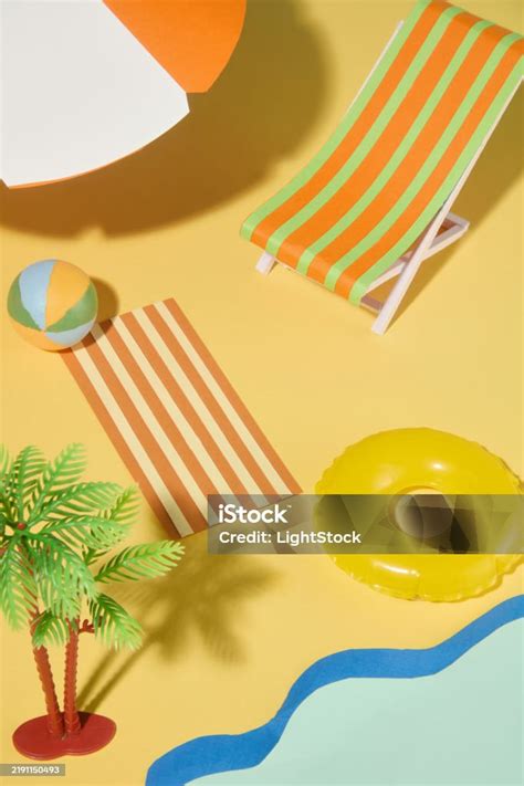 노란색 배경의 측면 모습에는 의자 매트 파라솔 파도 플라스틱 야자수가 있는 수제 종이 미니어처 해변 장면과 제품 전시를 위한 빈 공간이 있습니다 0명에 대한 스톡 사진 및