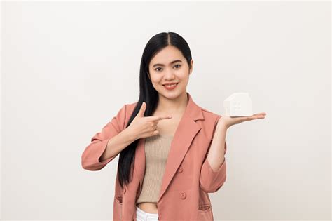 고립 된 흰색 배경에 서있는 집 조롱을 들고 젊은 귀여운 아시아 여성 부동산 및 주택 보험 개념 집 샘플 모델을 가진 비즈니스
