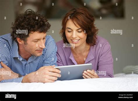 Showing The Wifey How Wi Fi Works A Couple Using A Digital Tablet While Lying On Bed Stock
