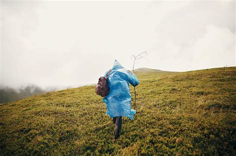 여행자 Hipster 여자 배낭 파란색 비옷에 안개 낀 산을 탐험 텍스트를 위한 공간입니다 대기 순간입니다 여행과 방 랑 벽 개념입니다 언덕에 걷는 여자 개념에 대한 스톡