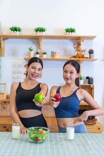 두 젊은 아름다운 사랑스러운 아시아 여자 여자의 사진 스포츠웨어를 입고 행복 빨간색과 녹색 사과와 샐러드를 선택 하 고 다이어트 하 고 건강 한 라이프 스타일을 위해 무게를