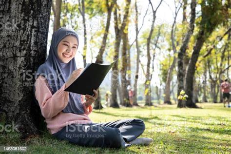 녹색 공원에서 담요에 앉아 머리 스카프를 두르고 화창하고 푸른 하늘로 책을 읽는 무슬림 여학생의 사진 25 29세에 대한 스톡 사진 및 기타 이미지 Istock