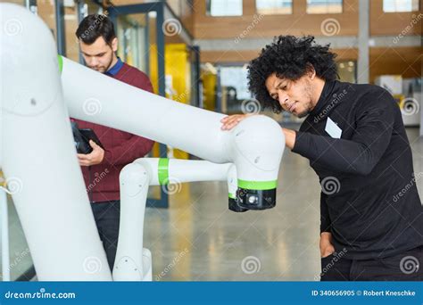 Engineers Working With A Robotic Gripper Arm In A Modern Industrial Setting Stock Image Image