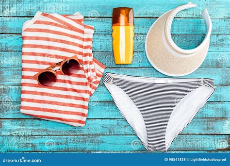 Top View Of Bikini Bottom Sunglasses Cap And Sunscreen On Blue Wooden