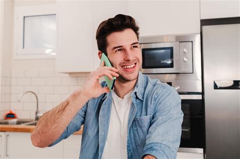 Apuesto Joven Llamando Por Teléfono Celular Y Sonriendo En La Cocina De