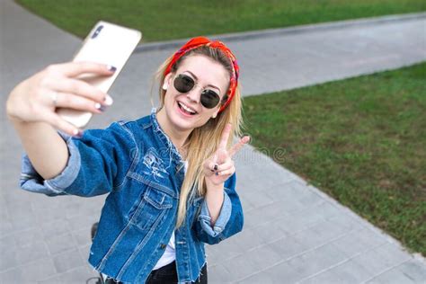 Stylish Happy Girl In Sunglasses A Denim Jacket And A Scarf Standing