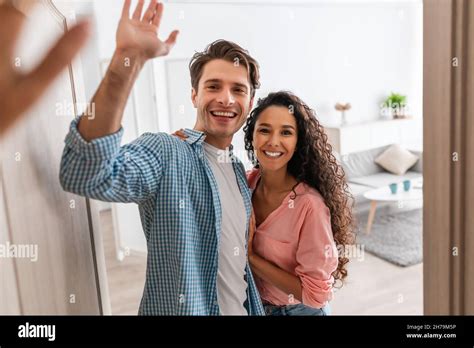Happy Couple Inviting People To Enter Home Giving High Five Stock