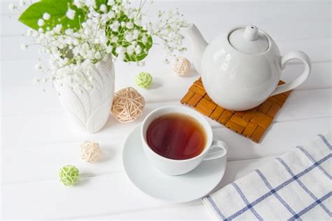 흰색 세라믹 컵과 차 주전자 흰색 나무 테이블 배경에 꽃병 아침 식사와 차 시간에 대 한 테이블을 설정 하는 아름 다운 좋은