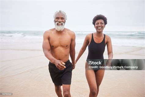 모래 해변을 산책하면서 웃고 있는 수영복을 입은 성숙한 커플 수영복에 대한 스톡 사진 및 기타 이미지 수영복 커플 중장년