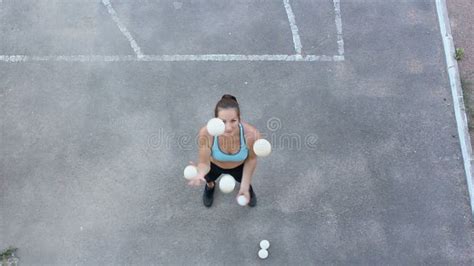 A Professional Juggler Juggles With White Balls An Attractive Girl
