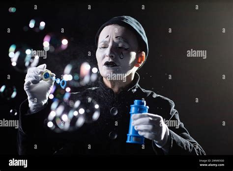 Minimal Portrait Of Mime Artist Blowing Soap Bubbles Against Black