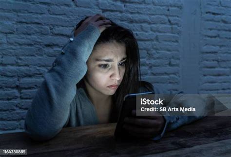 온라인 괴롭힘과 사이버 괴롭힘의 슬픈 젊은 여성 피해자의 극적인 초상화 스트레스와 두려움에 스마트 휴대 전화를보고 스토커에 대한
