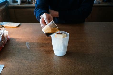 A Person Pouring Something Into A Cup On A Table Photo Free Food