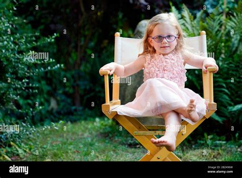 Portrait 3 Years Old Girl Sitting In Garden Chair Hi Res Stock