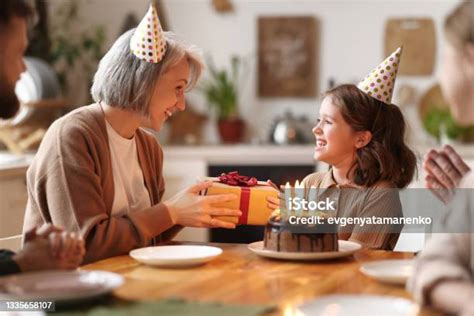 가족과 함께 생일 축하 하는 동안 흥분 된 행복한 손녀에 게 선물을 주는 사랑 하는 노인 여자 생일 선물에 대한 스톡 사진 및
