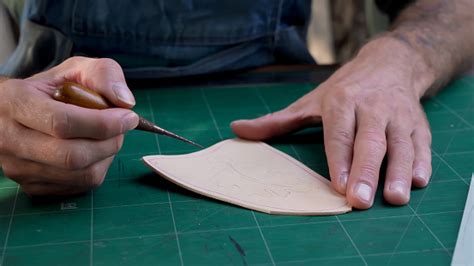 가죽 세공 도구의 클로즈업 손 소가죽에 프린트된 소가죽을 잘라 자르고 다듬어 소가죽 신발을 만듭니다 가죽 가방을 만들기 전에 꼼꼼하게 아름답게 자른 장인 가방에 대한 스톡