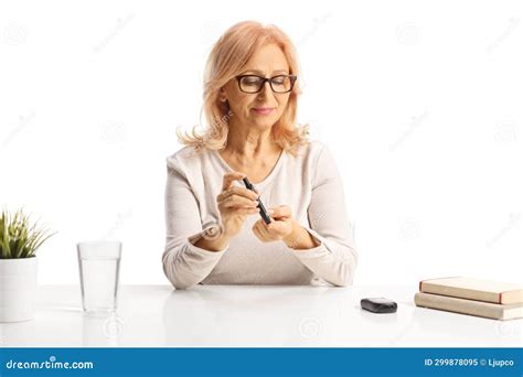 Mujer Que Se Inyecta Una Pluma De Insulina En El Dedo Y Sentado En Una Mesa Imagen De Archivo