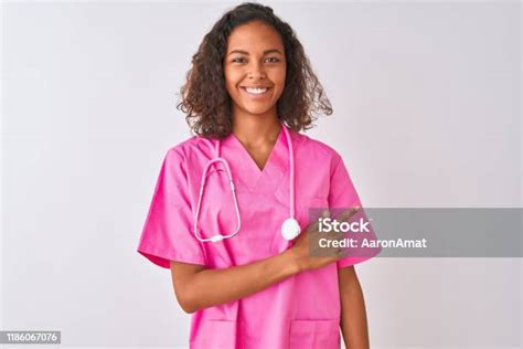 젊은 브라질 간호사 여성 청진기를 입고 고립 된 흰색 배경 에 서 쾌활한 얼굴의 미소와 함께 손과 손가락으로 측면에 행복하고 자연스러운 표정으로 가리키기에 대한 스톡 사진