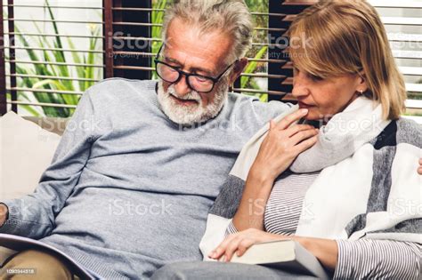 수석 부부 얘기 하 고 집에서 거실에 있는 소파에 함께 신문을 읽는 긴장 은퇴 부부 개념 가정의 방에 대한 스톡 사진 및 기타