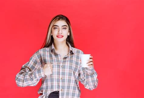 Fille En Chemise à Carreaux Tenant Une Tasse De Café Jetable Blanche Et
