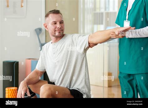Nurse asking patient to extend arm and tense muscles Stock Photo - Alamy