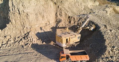 굴삭기가 돌을 싣고 덤프 트럭을 싣고 있는 건설 산업을 위한 사암 재료의 노천 광산의 조감도 유용한 광물 개념의 채굴 및 생산에 중장비 사진 Unsplash의 광업 이미지