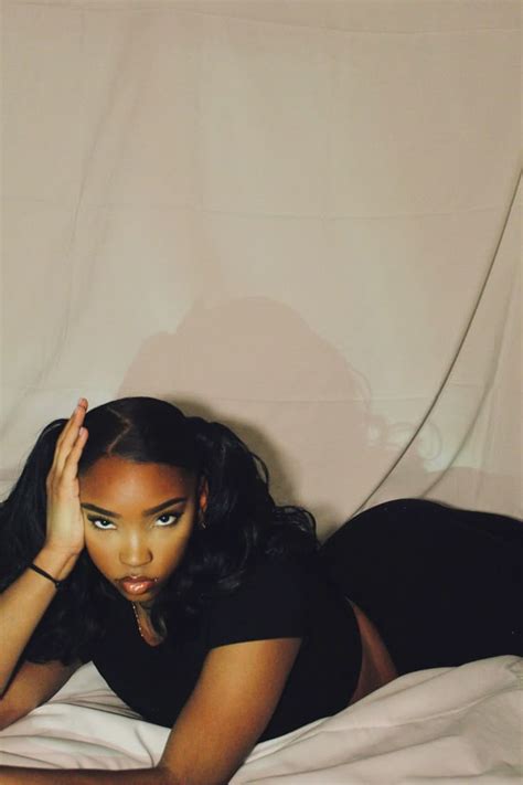 A Woman Laying On Top Of A Bed Next To A White Sheet Covered Wall With