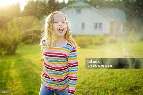 화창한 여름날 뒤뜰에서 스프링클러를 가지고 노는 사랑스러운 소녀 야외에서 물놀이를 하는 귀여운 아이 아이들을위한 재미있는 여름 게임 가든파티에 대한 스톡 사진 및 기타