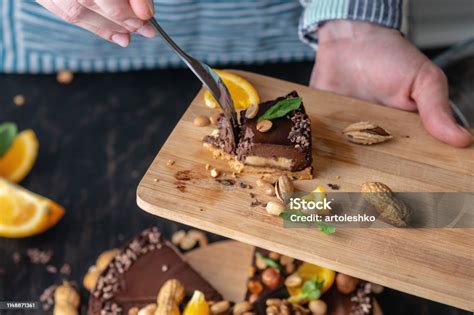 오렌지 민트 잎과 견과류와 초콜릿 케이크의 조각을 포크로 손 나누기 채식주의자를 위한 건강 한 생 디저트 감귤류 과일에 대한