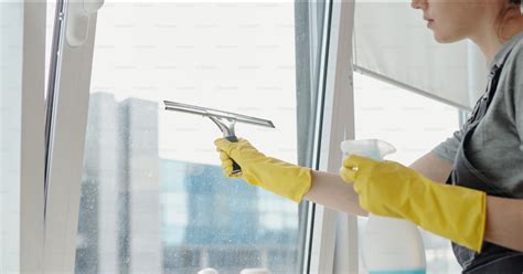 노란 장갑과 작업복을 입은 젊은 여성 청소부의 손이 세제와 실리콘 주걱으로 큰 사무실 창문을 닦고 있다 사진 Unsplash의 세탁 이미지