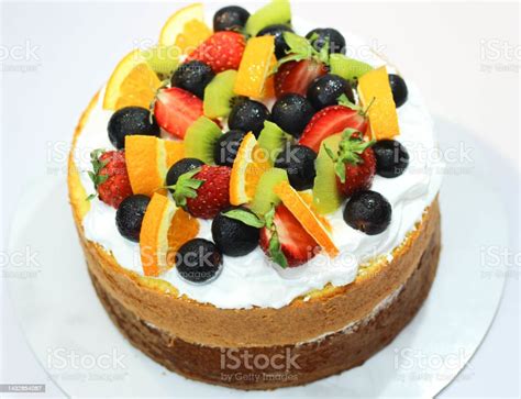 수제 Tres Leches 케이크와 머랭 프로스팅과 신선한 포도 키위 딸기 및 오렌지를 흰색 접시에 곁들입니다 흰색에 고립 된