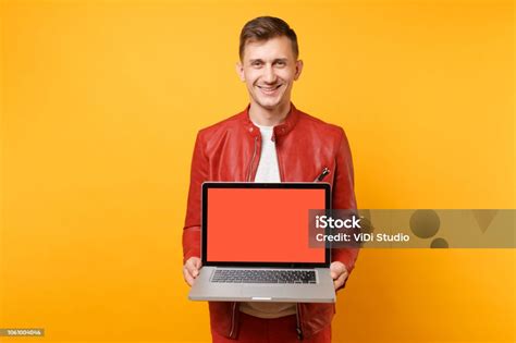 빨간색 가죽 재킷 T셔츠에서에서 젊은 남자 잡고 노트북 Pc 컴퓨터 빈 빈 화면이 밝은 노란색 배경에 절연 세로 보 그 재미