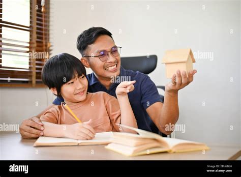 Cheerful And Caring Asian Dad Is Teaching His Little Son To Draw A