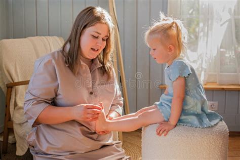 Mother Plays With Her Little Daughter And Tickles Her Bare Feet Sunny