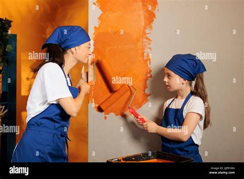 Maman Et Fille Utilisant De La Peinture Orange Sur Les Murs De La