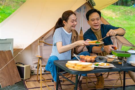 아시아인 커플은 아침에 친구들과 숲 속에서 캠핑을 하면서 함께 아침 식사를 요리한다 가정 생활에 대한 스톡 사진 및 기타 이미지