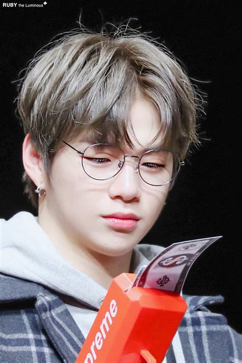 A Young Man With Glasses Is Holding An Orange Box And Looking At His