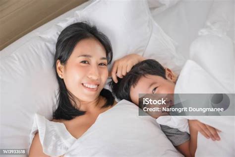 젊은 아시아 여성과 아들은 침대에서 자고 침실에서 휴식을 취합니다 그들은 옆으로 누워서 눈을 감고 긴장을 풀고 있습니다 카메라를