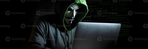 Unveiling The Enigmatic World Of Cybercrime A White Masked Hacker S Front View Amidst Dark Hood
